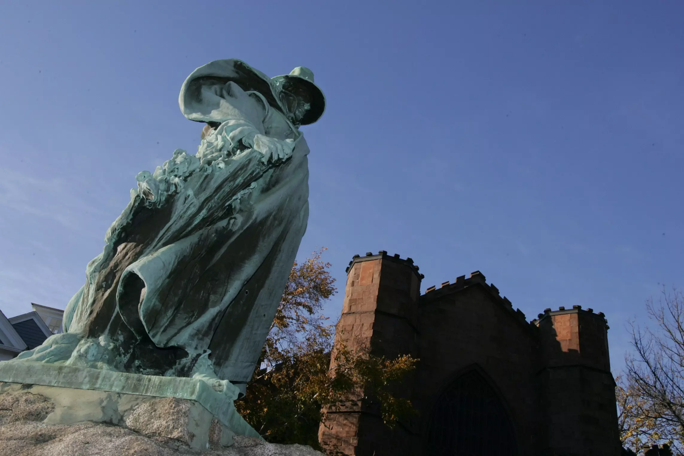 Una statua all'esterno del Museo delle streghe di Salem si staglia contro un cielo viola brillante.