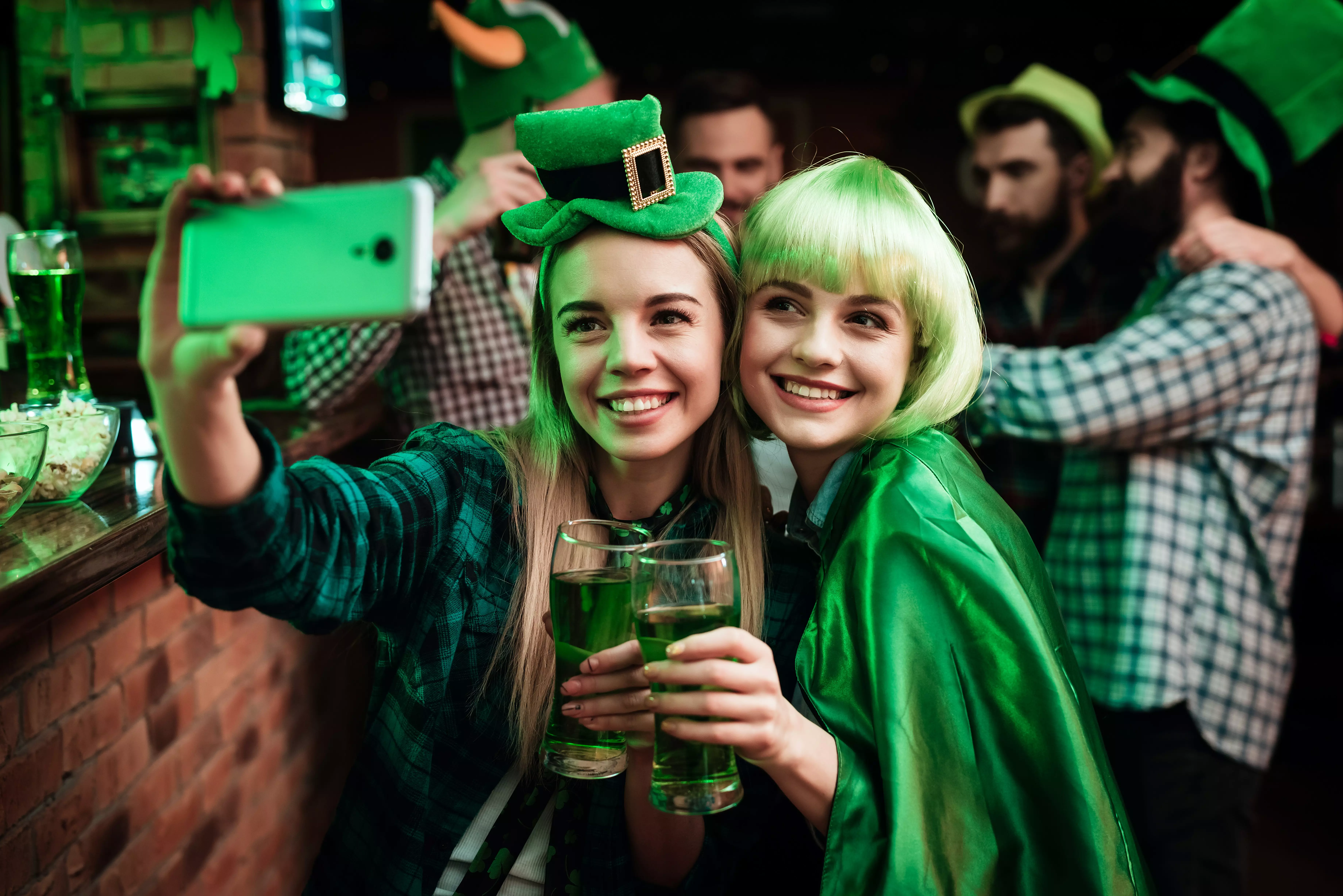 Dua budak awéwé dina buuk palsu sareng topi nyandak selfie, anu peryogi caption Poé St. Patrick 2022 pikeun Instag...