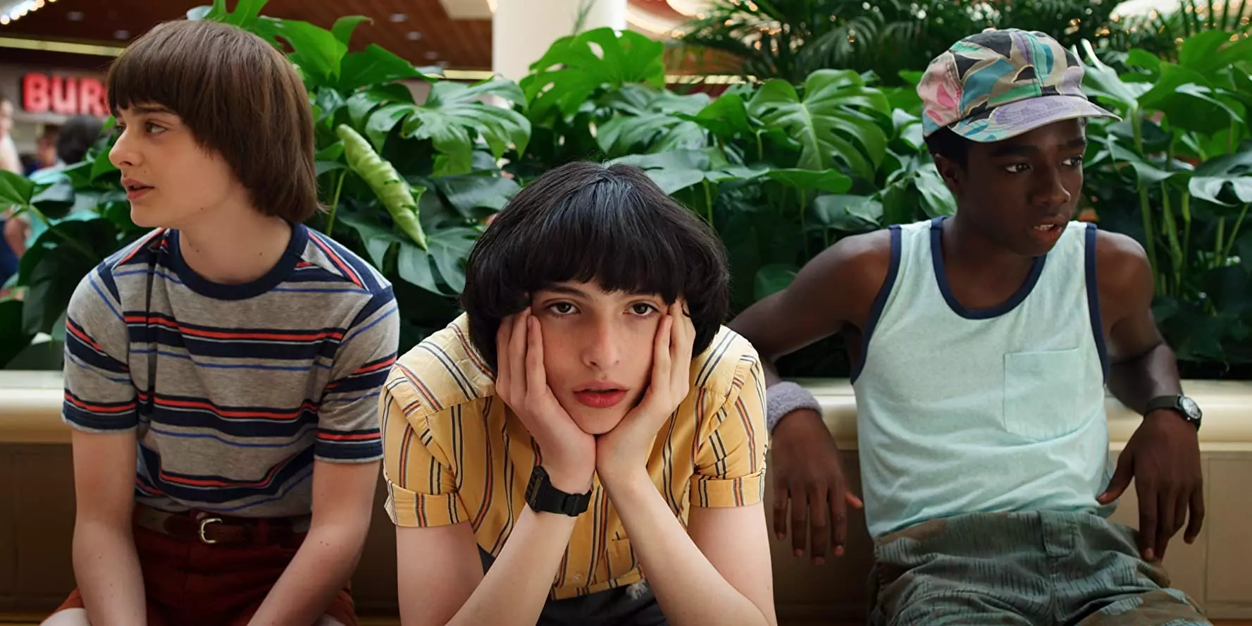 De Will, de Mike an de Lucas vum Netflix 'Stranger Things' sëtzen op enger Bänk an der Starcourt Mall a waarden ...