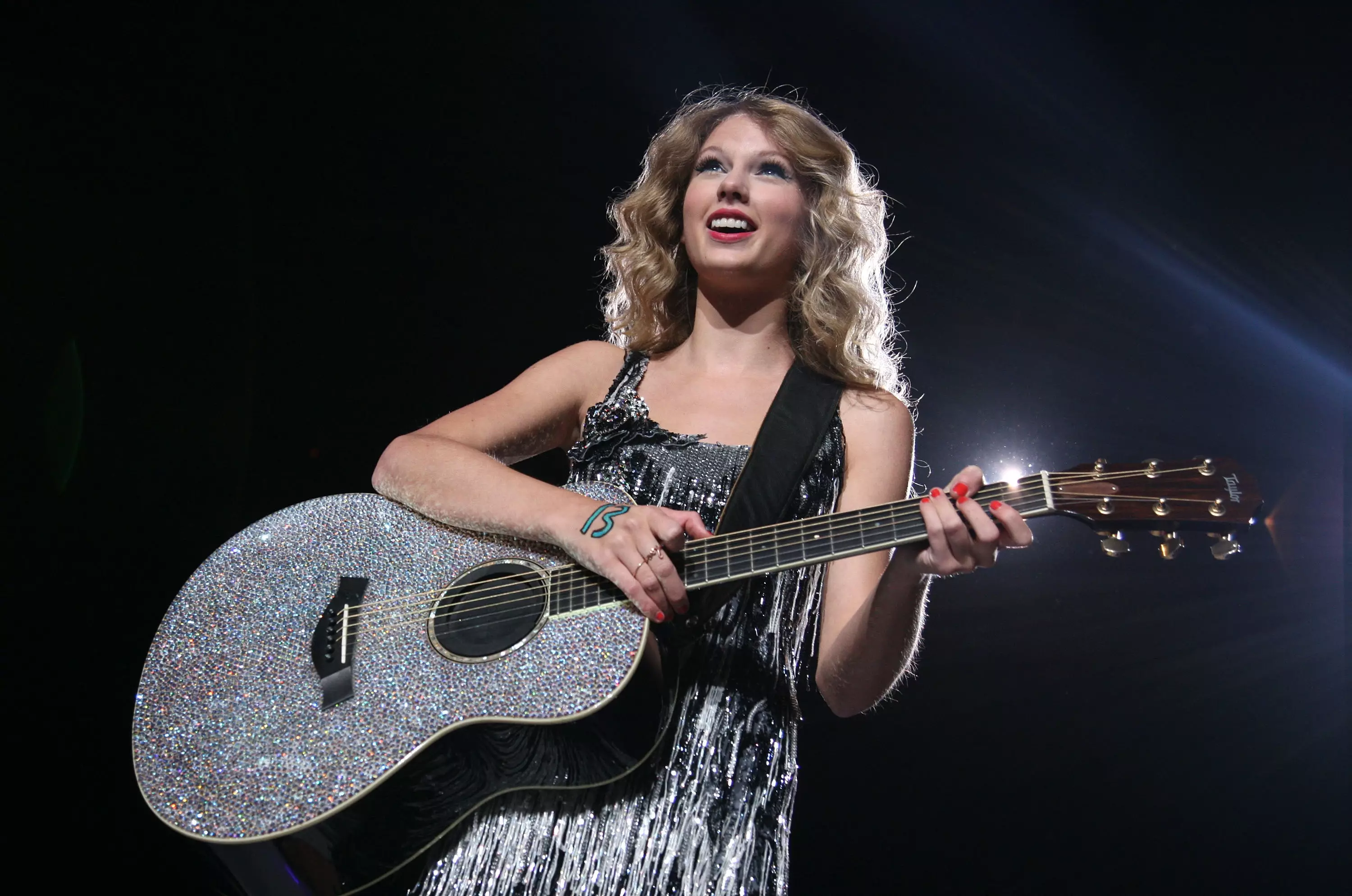 Taylor Swift ezüst gitárral és ruhával lép fel a „Fearless” korszakában.