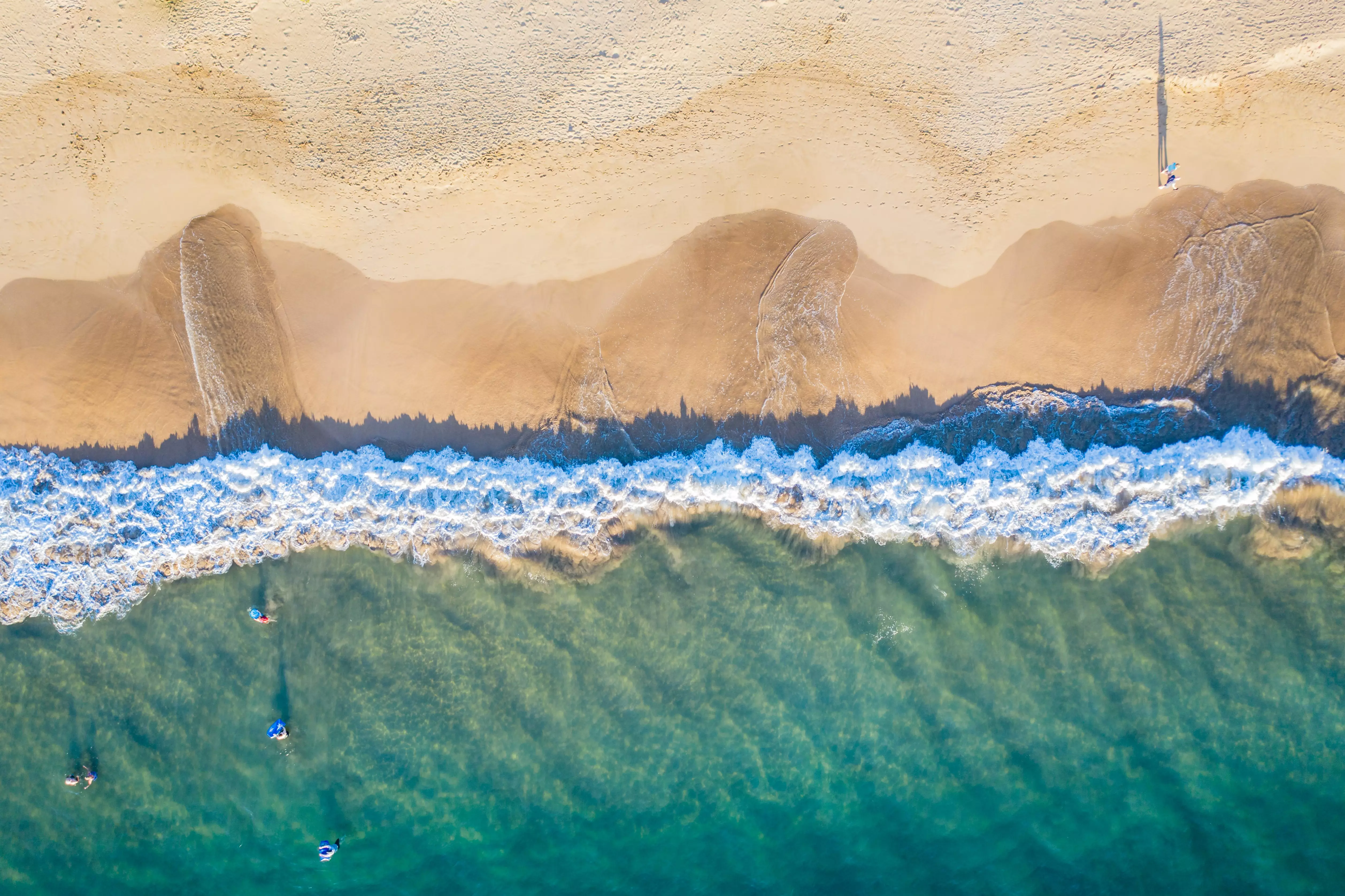 Een luchtfoto van een strand in Maui, Hawaii, toont blauwgroen water en helder zand.