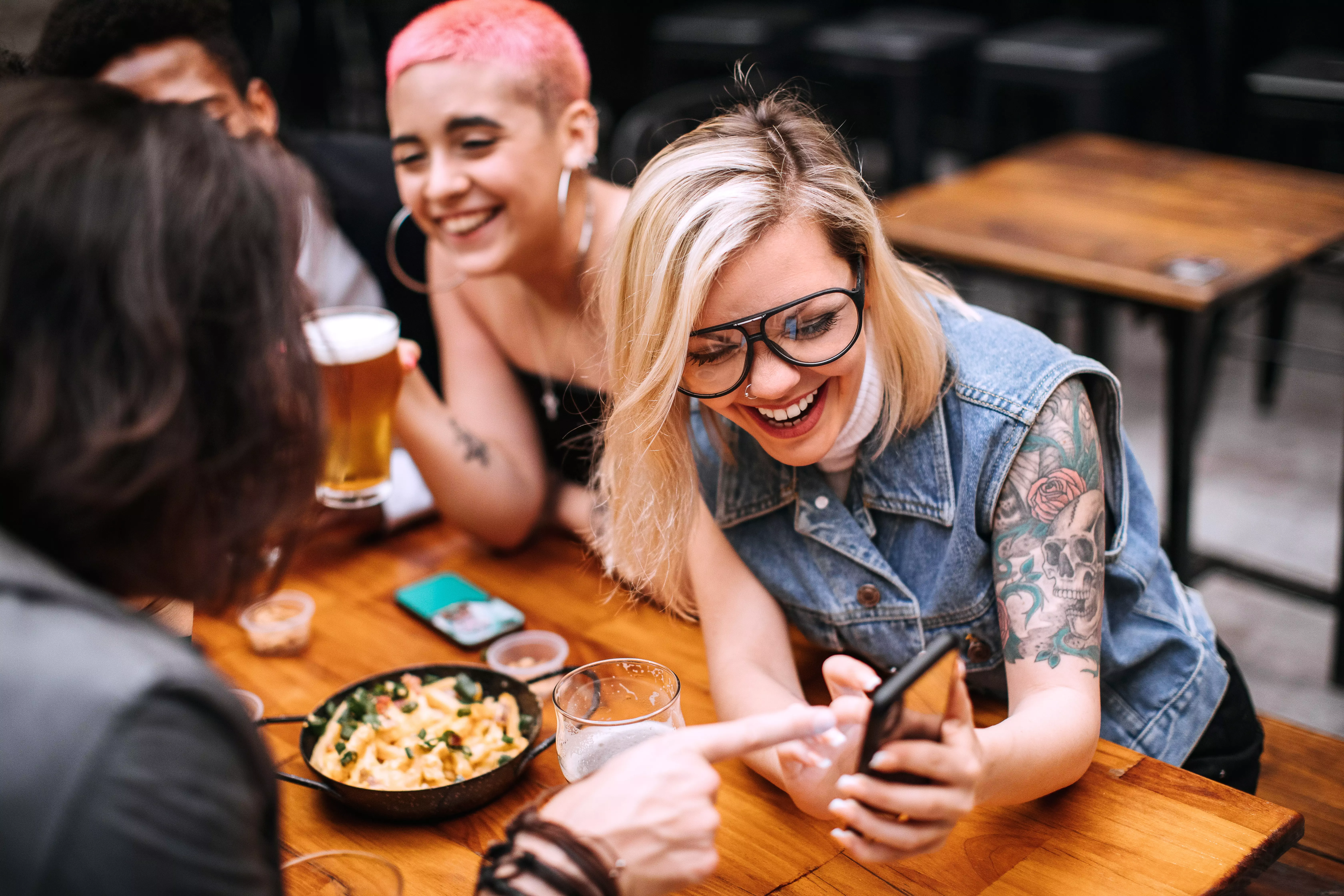 Um grupo de amigos ri de nomes inapropriados de bate-papo em grupo em um bar.