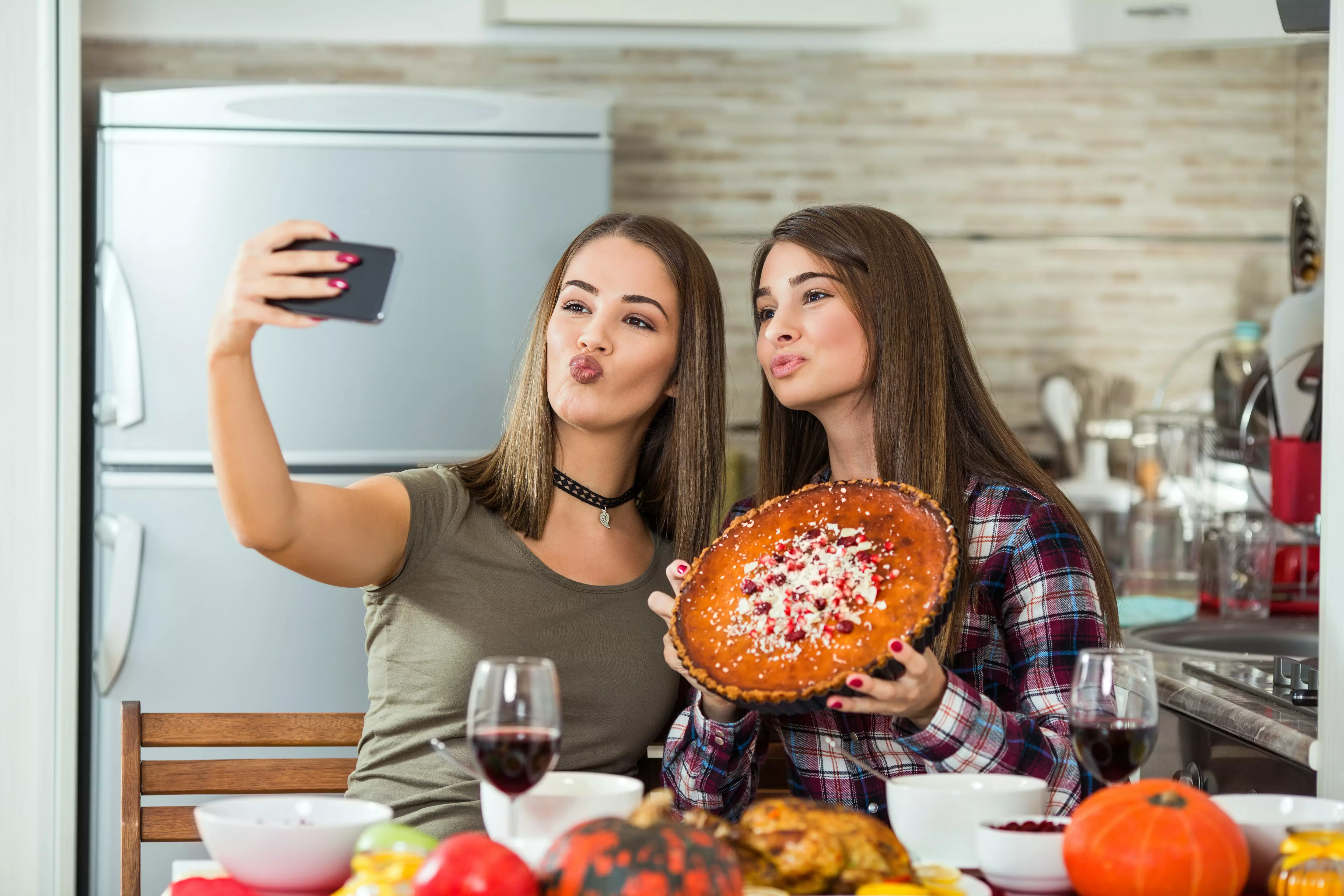 Laba gabdhood oo brunette ah ayaa isu soo taagay sawir-selfie oo ay ku jiraan pie baradho macaan ee Thanksgiving.