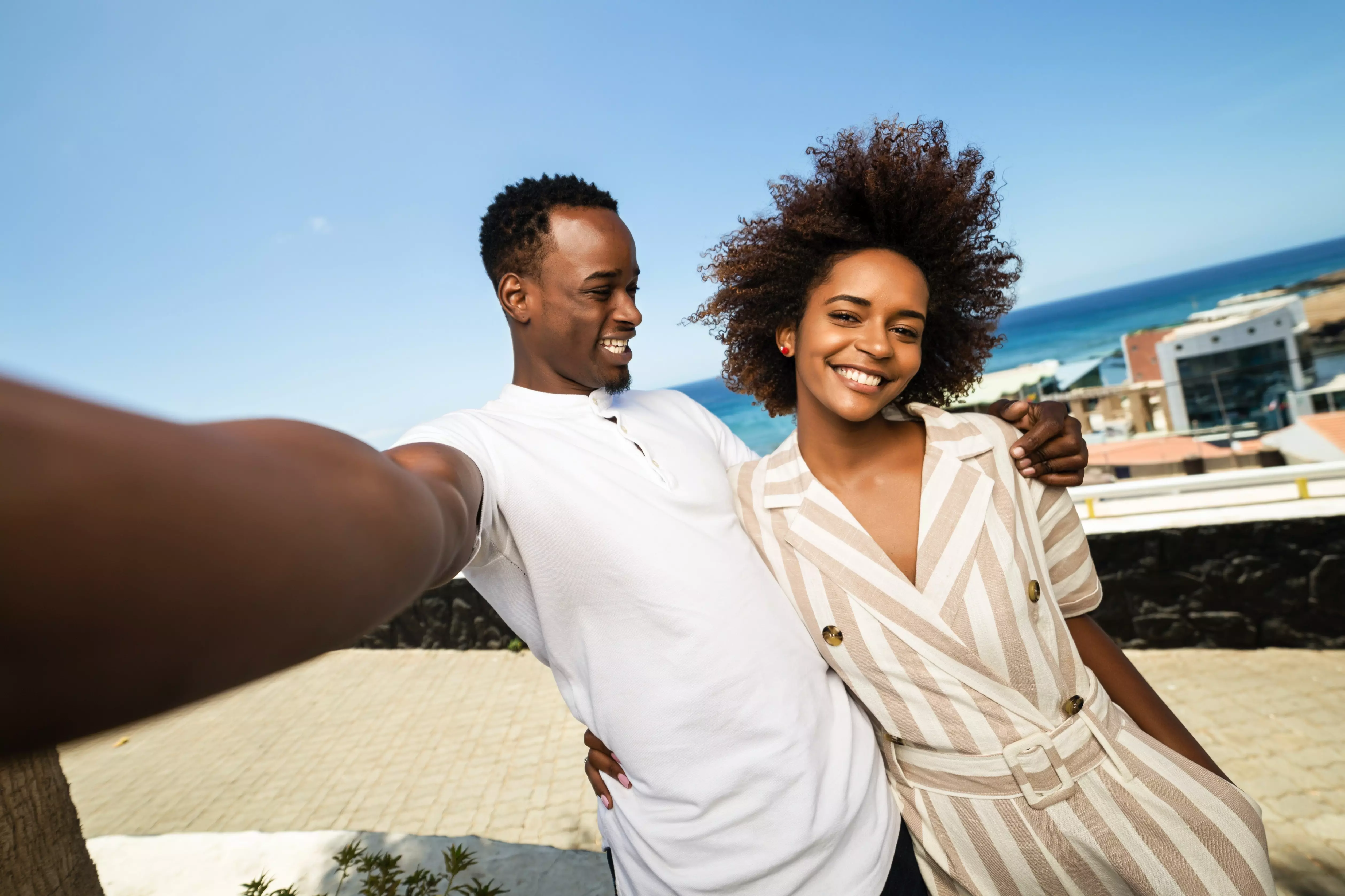 Retrato ao ar livre do casal afro-americano negro tomando uma selfie